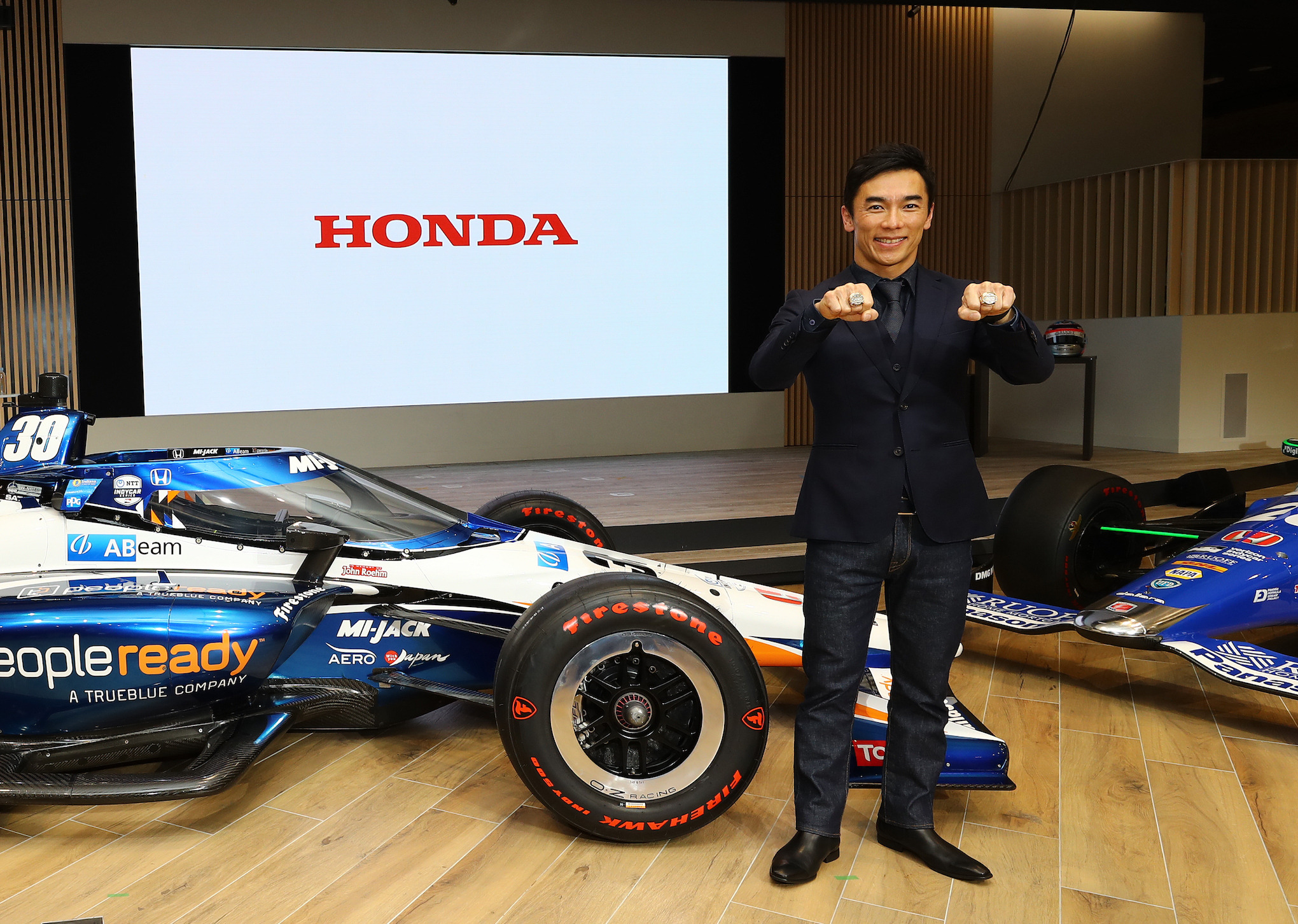 インディ500で2勝目達成の佐藤琢磨、2台の優勝車の前で“凱旋報告 インディ500で2勝目達成の佐藤琢磨、2台の優勝車の前で“凱旋報告